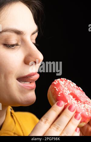 A woman is going to eat a donut, sniffs it and licks it. The smell and ...