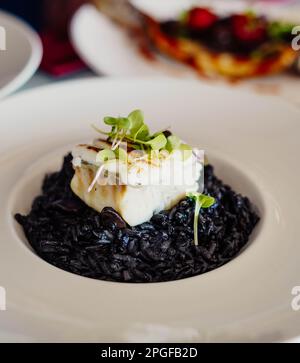 Arroz negro (Spanish squid ink rice) cooked in a big flat pan with ...
