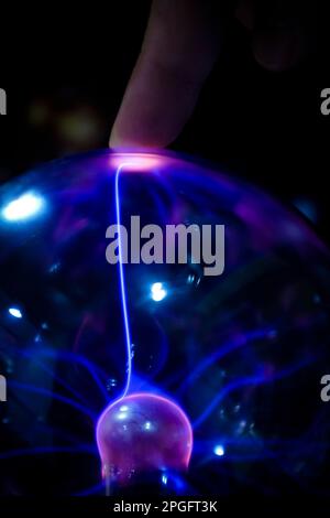Finger touching an energy ball with a lightning light ray crossing a ...