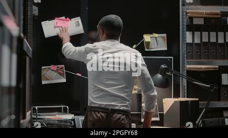 Law officer studying clues on case files in police archive office ...