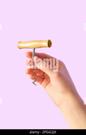 Female hand holding corkscrew on lilac background Stock Photo - Alamy