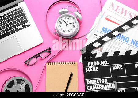 Notebook with movie clapper, alarm clock, film reel and laptop on blue ...