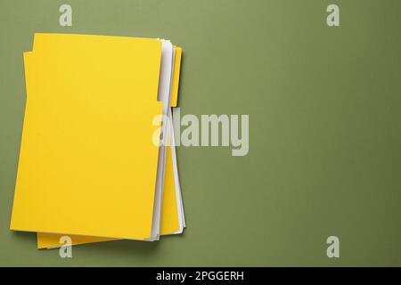 Yellow files with documents on olive background, top view. Space for ...