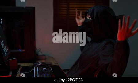 Hacker in hoodie raising hands while having problem with hacking ...
