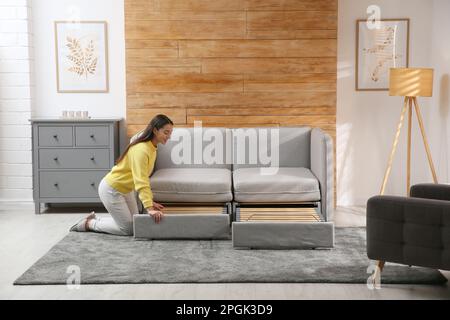 Young woman unfolding sofa into a bed in room. Modern interior Stock ...