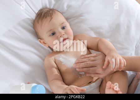 Mother applying dusting powder onto her baby on bed, top view Stock ...
