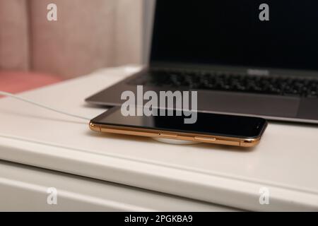 Smartphone with wireless charger connected to laptop on light grey ...