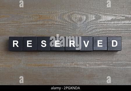Word RESERVED made with cubes on wooden surface, top view. Table ...