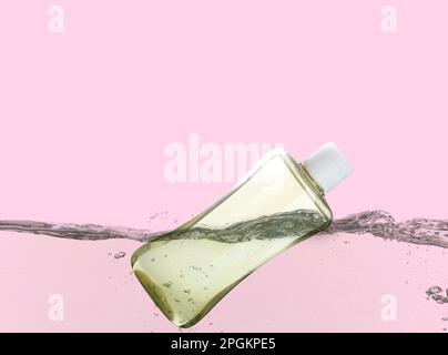 Bottle of baby oil floating in water against pink background Stock ...