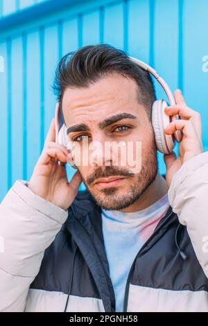 Man wearing bluetooth headphones holding smart phone at station Stock ...
