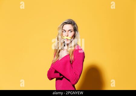 Blond woman imitating mustache standing against green background Stock ...