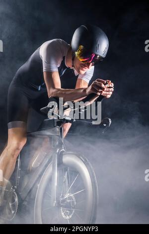 Cyclist sitting on turbo trainer against black background Stock Photo ...