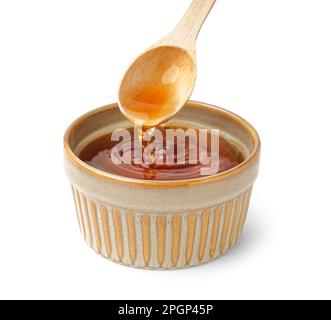 Pouring of tasty maple syrup from bottle into spoon on white background ...