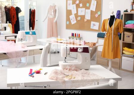 Dressmaking workshop interior with stylish female clothes and equipment ...