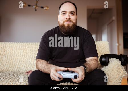 Focused male gamer dressed entirely in black clothing with a gaming ...