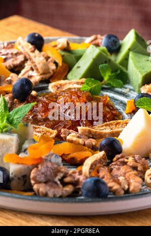 Close-up of various cheeses and nuts snacks on wooden plate placed on ...