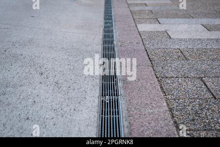 Stainless steel grated flood water storm drain on a Tokyo sidewalk ...
