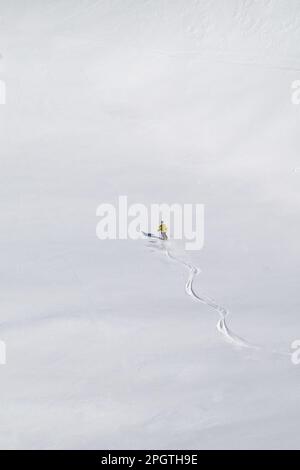 Single freeriding skier making fresh first tracks in recent powder snow ...