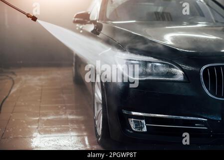 High pressured water. Modern black automobile get cleaned inside of car ...