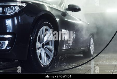 High pressured water. Modern black automobile get cleaned inside of car ...