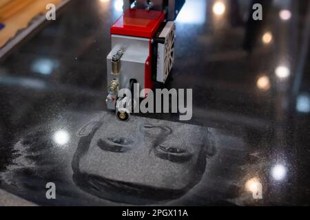 Stone engraving machine etching portrait on black granite gravestone ...
