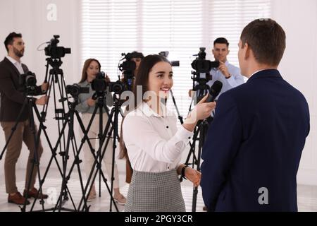Professional young journalist interviewing businessman and group of ...