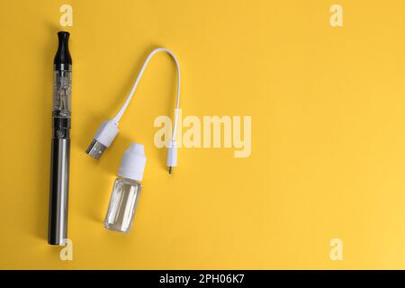 Reusable electronic cigarette and USB charger on yellow background ...