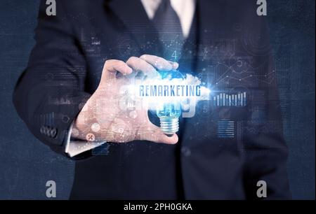 Businessman holding a light bulb with REMARKETING inscription, new ...