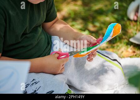 Children paper crafting with parents in outdoor children party ...