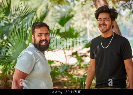 Two funny indian men laughing and speak Hindi in public park green palm ...