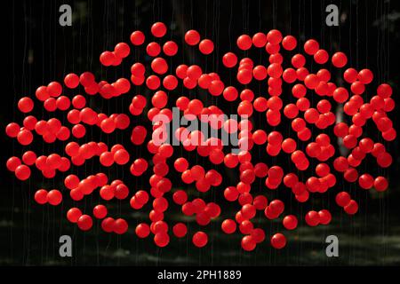 Red balls suspended on wire, outdoor art object symbolizing blood cells ...