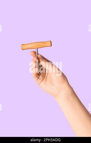 Female hand holding corkscrew on lilac background Stock Photo - Alamy