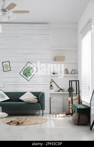 Interior of messy room with green sofa and overturned furniture after ...