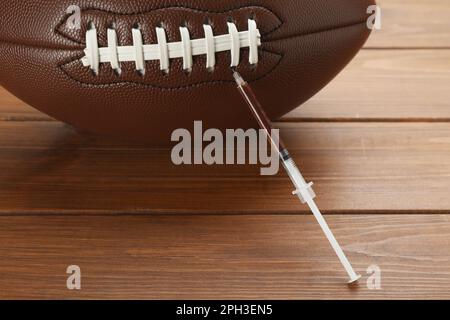 American football ball with syringe on black background, closeup ...