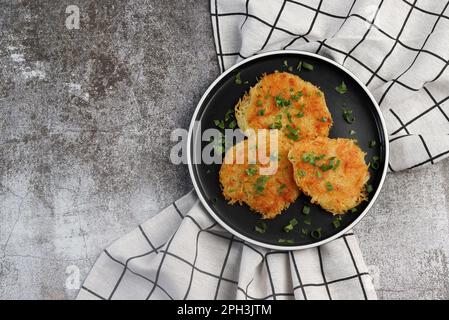 Rustic hash browns with chives on a round plate on a dark background ...