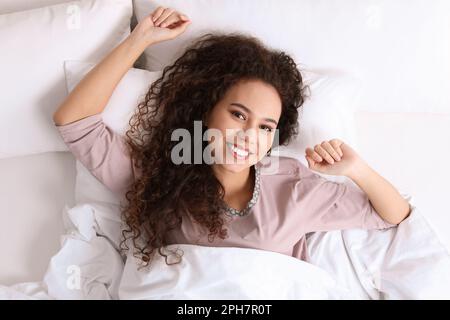 Happy African American woman awakening in bed, top view Stock Photo - Alamy