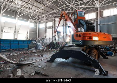 Excavator grabs trash in warehouse of waste processing plant Stock ...