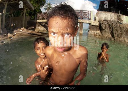 Boys playing by jetty in shallow water, Ambon, Indonesia Stock Photo ...