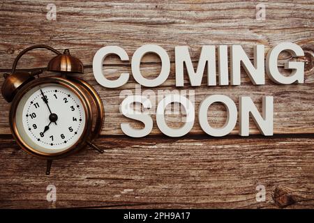 Coming Soon alphabet letter and alarm clock on wooden background Stock ...