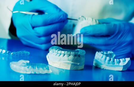 a dentist is adjusting an occlusal splint, using a metal tool, in a ...