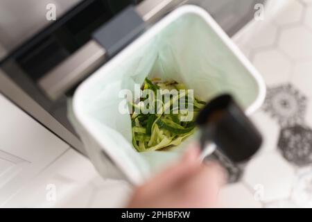 Woman putting food leftovers in undifferentiated waste bin, improper ...