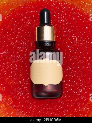 Cosmetic bottle with blank label lies on stone on light pink, palm leaf ...