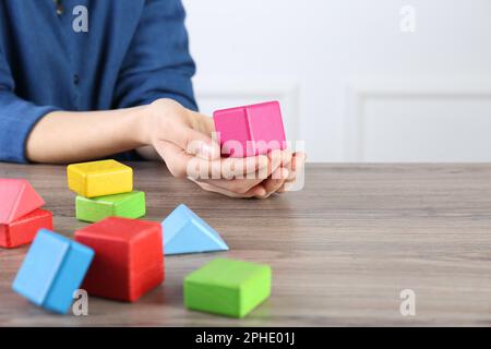 ABA therapist with colorful building blocks at wooden table, top view ...