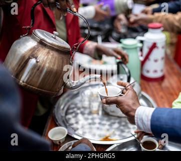 Pouring dark coffee from a communal pot into cups in Ethiopia Stock ...
