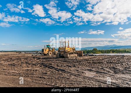 Two bulldozer tractors parked on dirt which has lots of tread tracks in ...
