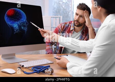 Neurologist showing brain scan to sad man in clinic Stock Photo - Alamy