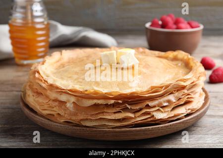 Stack of delicious crepes with melting butter on wooden table, space ...