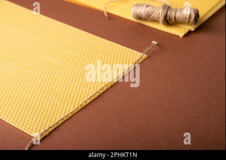 Beeswax honeycomb candle sheets and jute thread on brown background ...