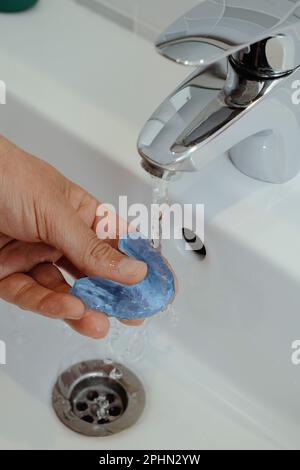 closeup of a man cleaning his blue occlusal splint using a toothbrush ...