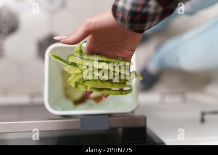 Cook throwing cucumber peels in a bokashi container for decomposition ...